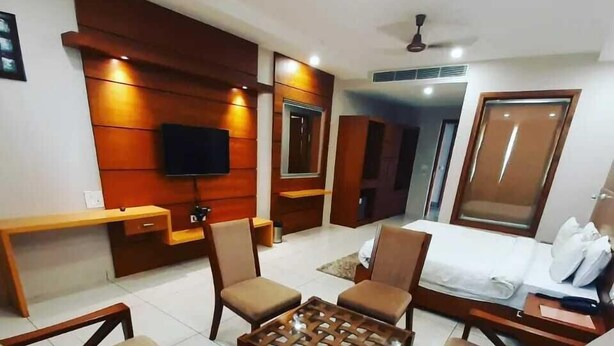 Quarto de hotel moderno com sofá, mesa de centro, televisão e cama.