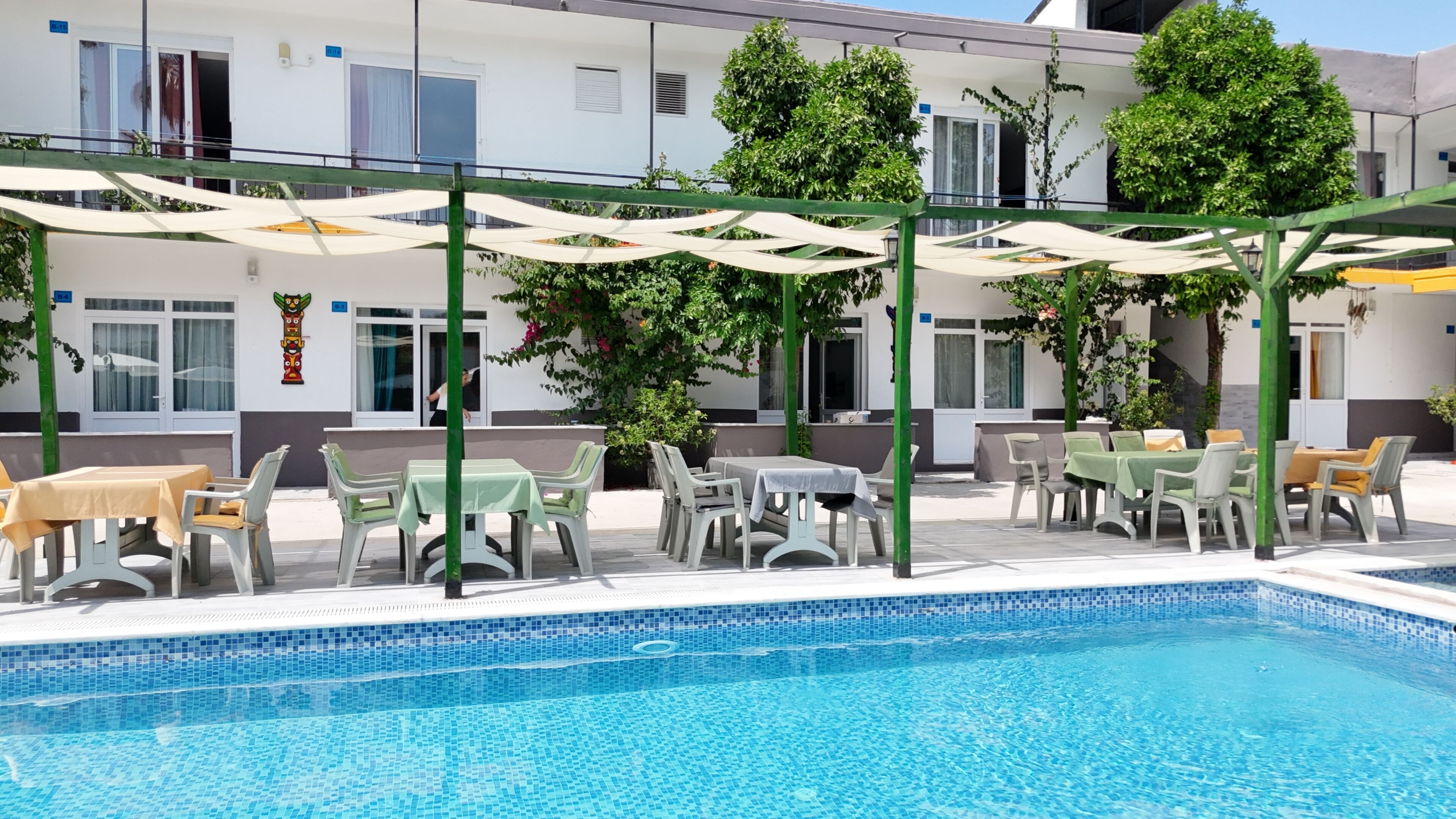 Uma área à beira da piscina com assentos externos e uma piscina azul cristalina.