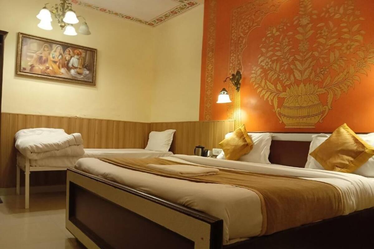Quarto de hotel com uma cama, uma cadeira, um quadro e uma parede com um desenho floral.