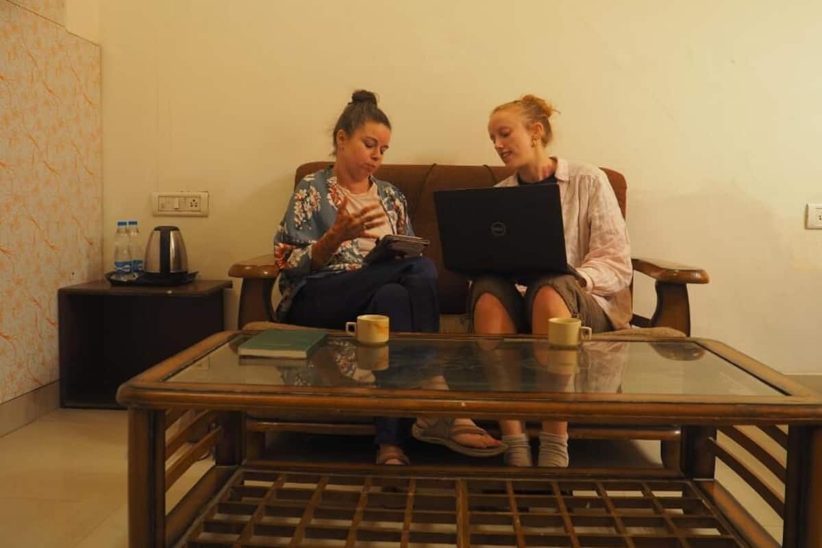 Duas pessoas sentadas num sofá com um laptop e uma mesa de vidro à frente.