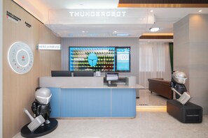 Uma receção moderna com um ecrã digital, uma figura de robô e um aviso a indicar 'THUNDERBOT'.