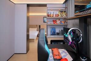 Quarto de hotel moderno com equipamento de jogos, cama e minibar.