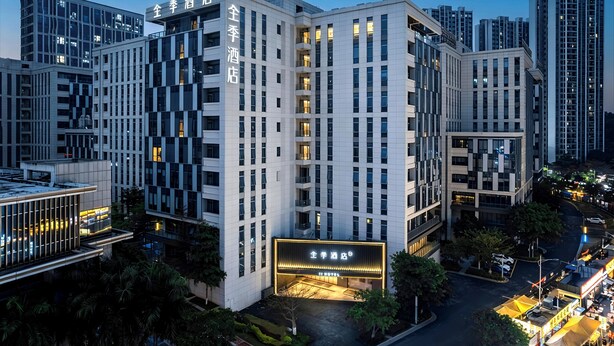 Um hotel moderno com vários andares, uma entrada marcante e fachada bem iluminada.