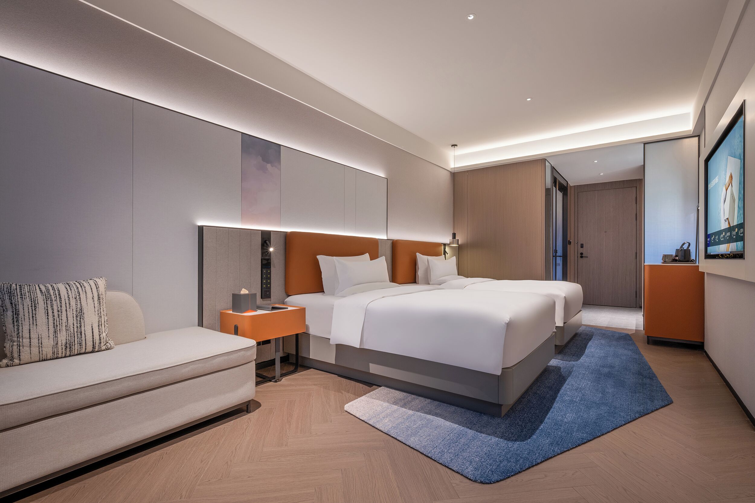 Quarto de hotel moderno com cama, sofá, escrivaninha e um espelho grande.