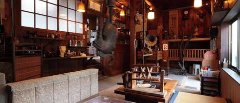 Interior tradicional em estilo japonês, com vigas de madeira, piso de tatame e bancada de pedra.