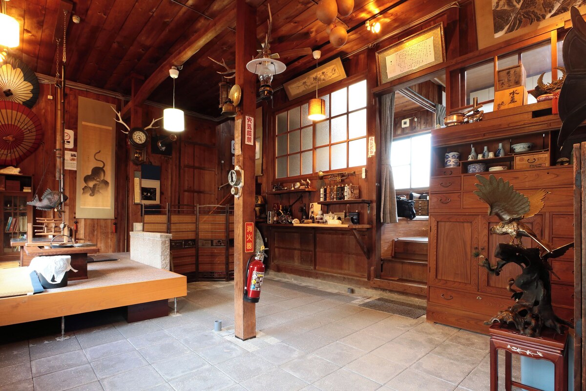 Um interior japonês tradicional com vigas de madeira, tatames e diversas decorações culturais.
