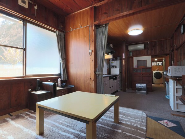 Interior de cabana com mesa de jantar, cozinha e uma grande janela.