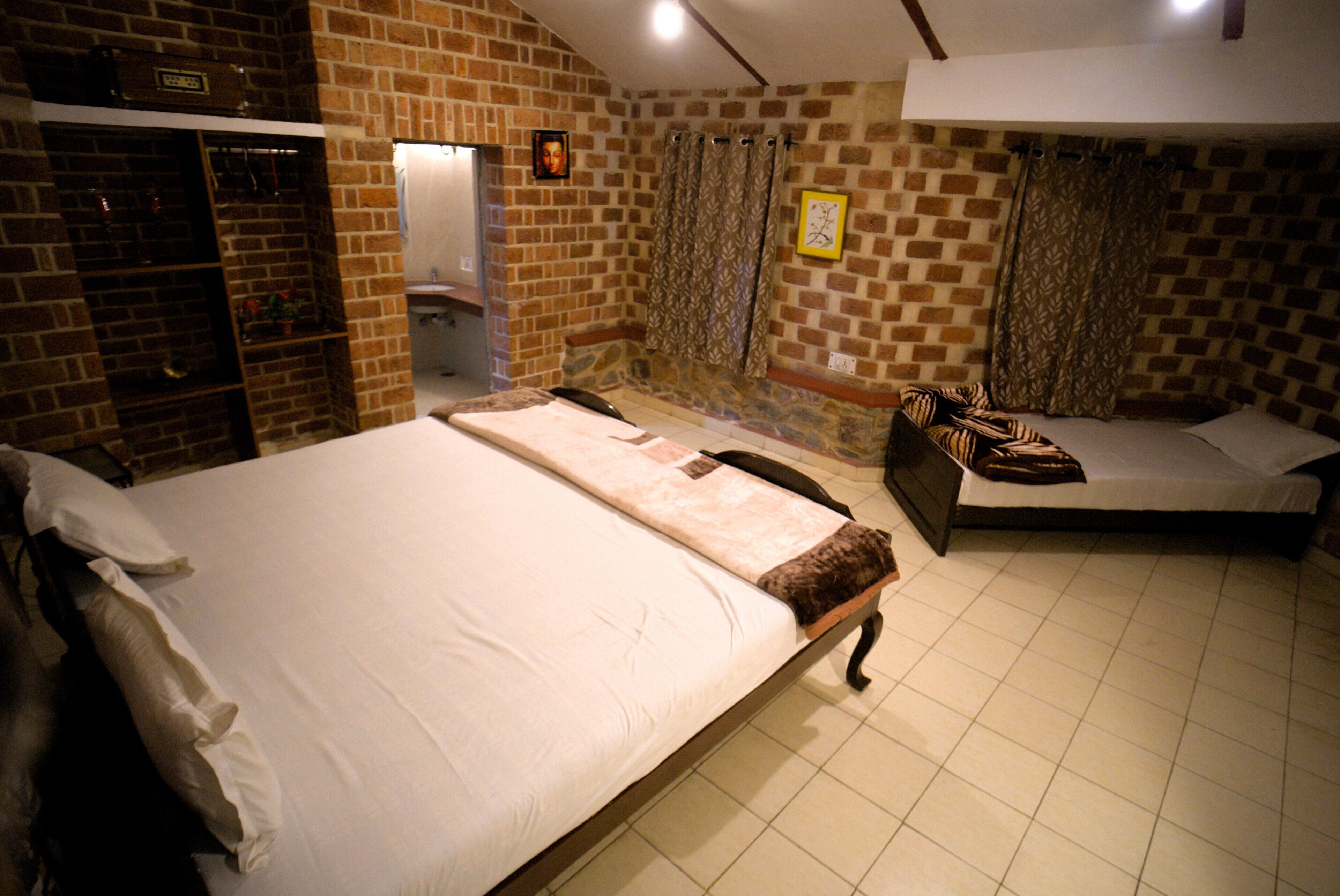 Quarto com uma cama grande, guarda-roupa, espelho e parede de tijolos.