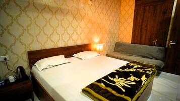Quarto de hotel com cama, mesa de cabeceira, luminária e guarda-roupa.