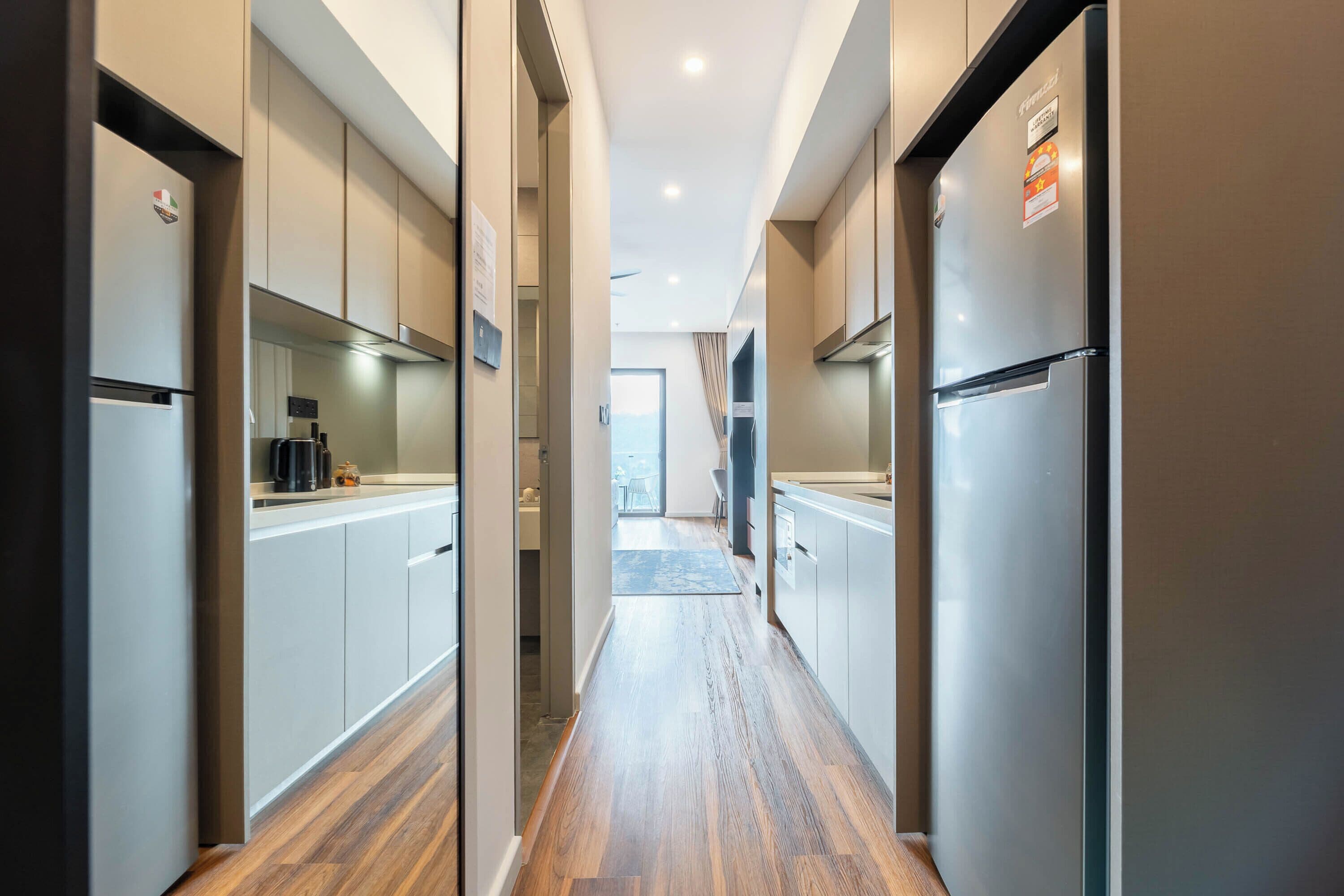 Cozinha moderna com eletrodomésticos de aço inoxidável, piso de madeira e vista para a sala de jantar.