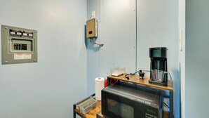 Uma cozinha compacta com micro-ondas, cafeteira e uma tomada com temporizador.