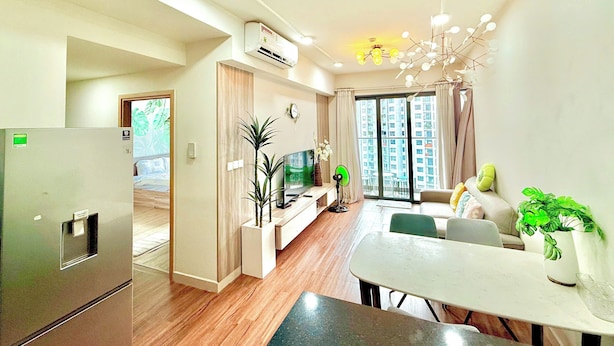Uma sala de estar moderna com área de jantar, cozinha e uma grande janela com vista para a cidade.