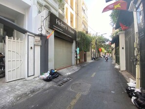 Uma rua estreita com lojas fechadas, portão e uma motocicleta estacionada.
