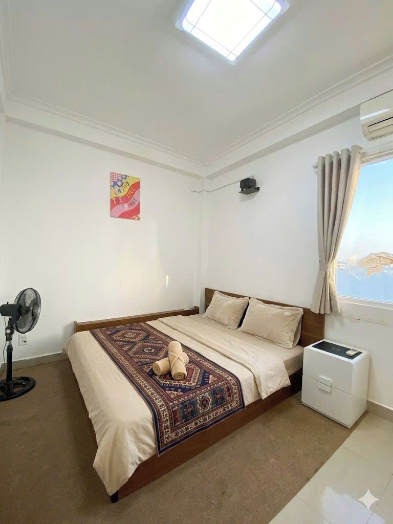 Quarto com cama, ventoinha, ar condicionado e janela com cortinas.