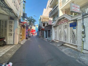 Uma rua estreita com edifícios em ambos os lados, alguns com placas indicando estabelecimentos comerciais.