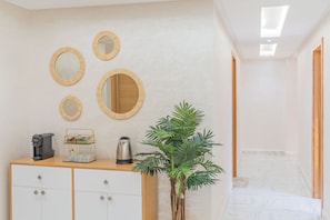 Quarto de hotel com um armário de madeira, cafeteira, chaleira e uma planta em vaso.