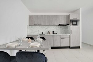Uma cozinha moderna com armários cinza, bancada de mármore e micro-ondas embutido.
