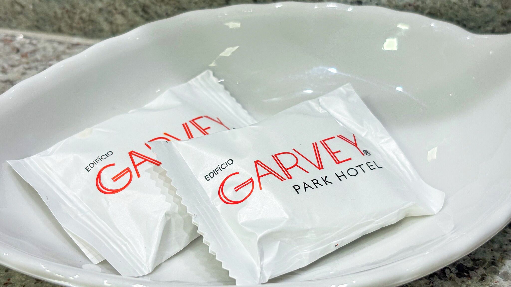 Uma tigela branca com dois pacotes brancos, com a inscrição 'GARVEY PARK HOTEL'.