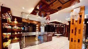 Um lobby moderno com divisória de vidro, painéis de madeira e área de estar com sofás e uma mesa de centro.