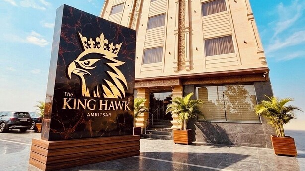 Entrada de hotel com uma grande placa indicando 'The King Hawk Amritsar'.
