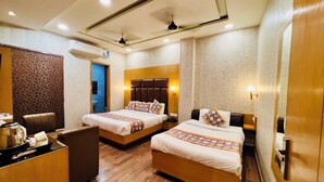 Quarto de hotel com duas camas, uma escrivaninha, uma cadeira, um guarda-roupa e um banheiro.