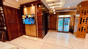 Um hall com televisão, geladeira e divisória de madeira.