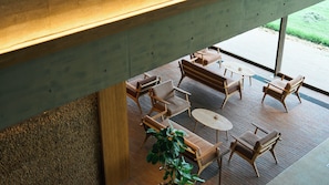 Um interior moderno com mobiliário de madeira, uma janela ampla e teto de concreto.