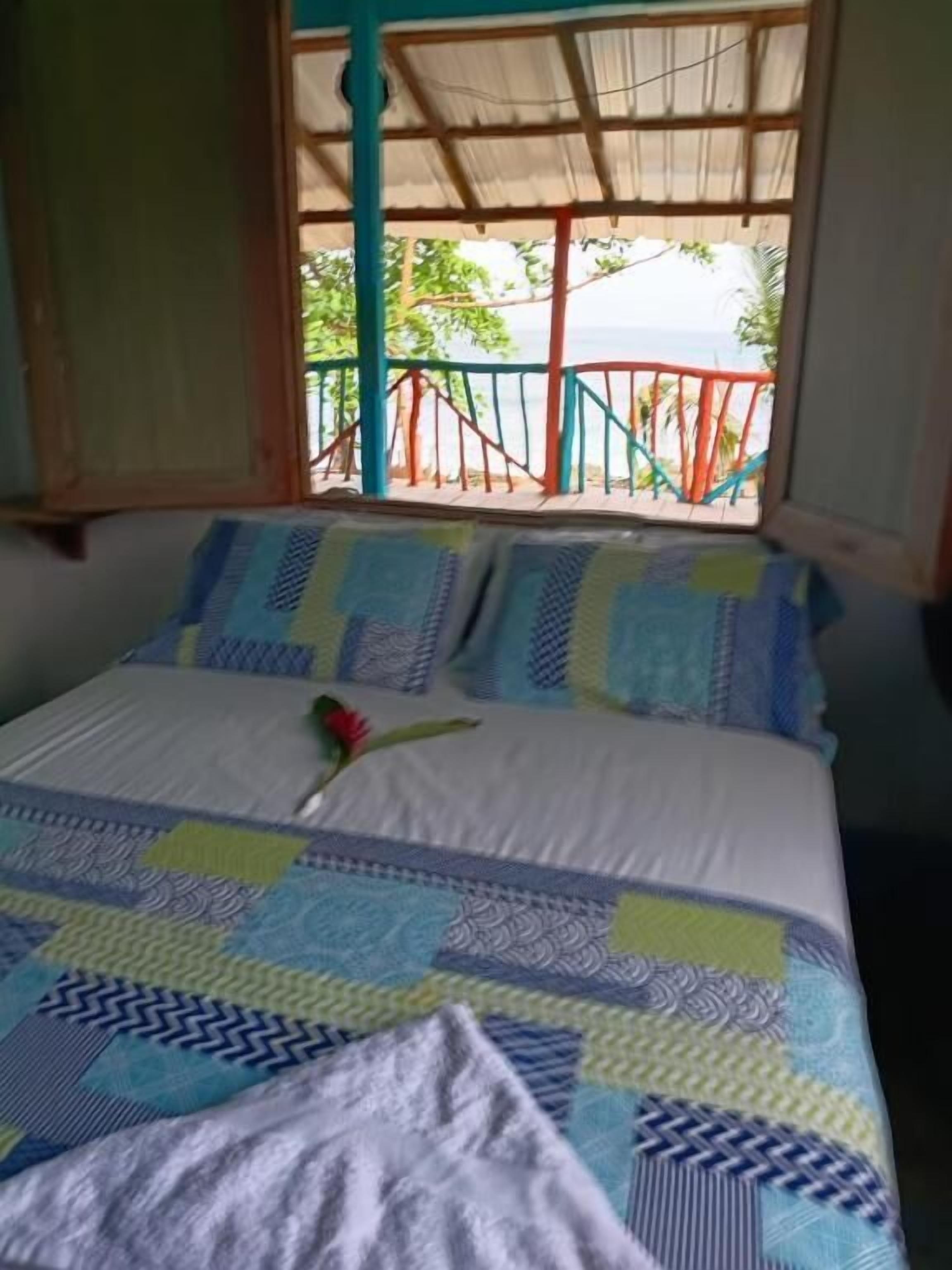 Uma cama com colcha estampada, um travesseiro e uma pena vermelha.