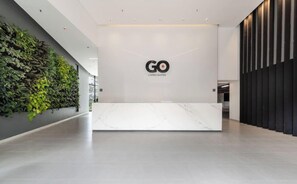Uma receção moderna com um logotipo, uma parede verde com plantas e um design minimalista.