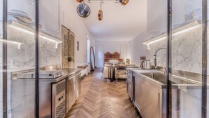 Cozinha moderna com bancadas de mármore, eletrodomésticos de aço inoxidável e piso de madeira em padrão herringbone.