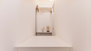 Um banheiro minimalista com toucador branco, espelho e prateleira pequena com objetos decorativos.