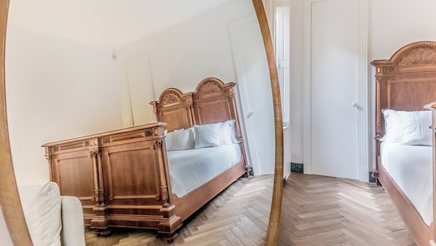 Quarto com cama de madeira, mesa de cabeceira e uma cadeira.
