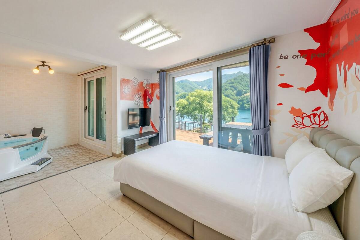 Quarto de hotel com cama, banheira, televisão e varanda com vista.