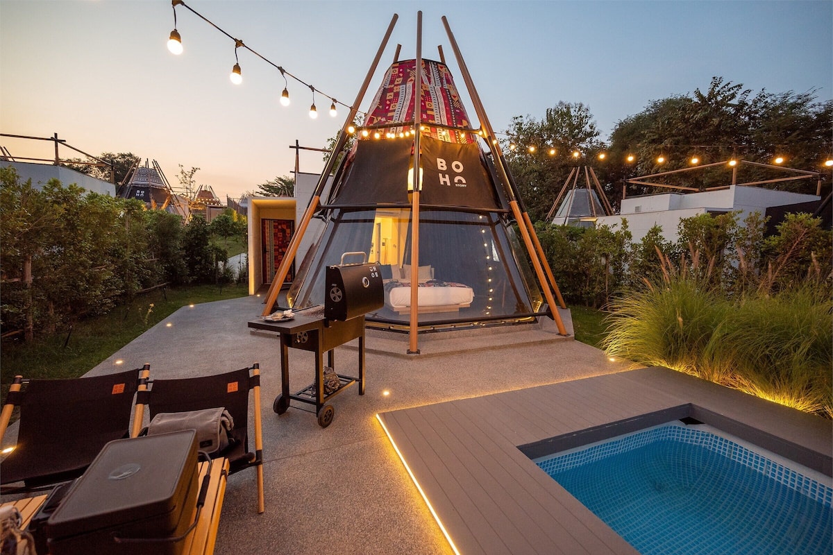 Uma estrutura em forma de tenda com churrasqueira, piscina e luzes de cordão.