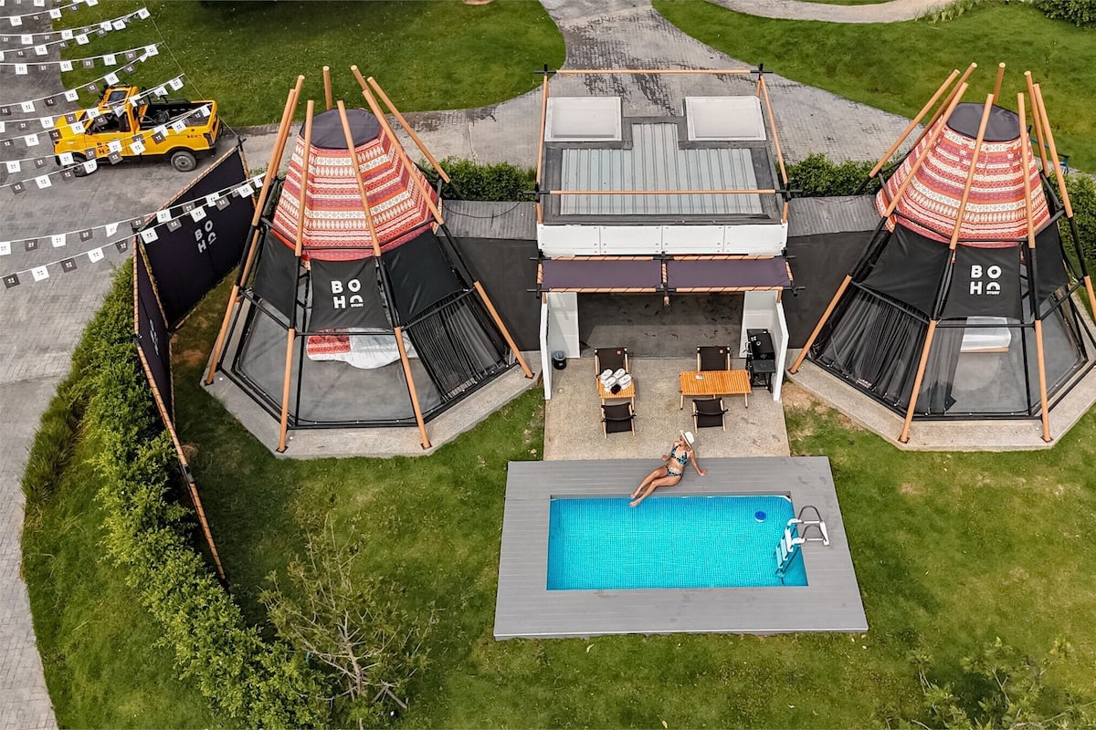 Uma área de piscina no terraço com duas tendas, piscina e um veículo amarelo.