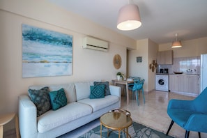 Uma sala de estar com sofá, mesa de centro e área de jantar com cadeiras.