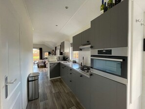 Cozinha moderna com armários cinza, exaustor de aço inoxidável e forno embutido.