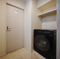 Uma lavanderia com porta fechada, uma máquina de lavar e uma prateleira pequena.
