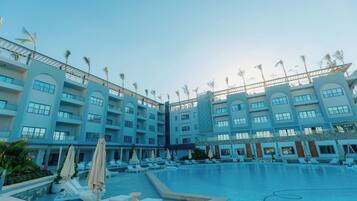 Um hotel com piscina, espreguiçadeiras e palmeiras.