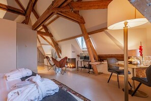 Um quarto com teto inclinado, lareira, área de jantar com cadeiras e uma mesa.