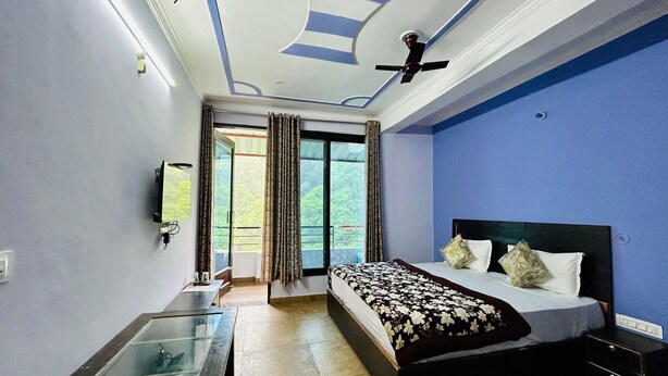 Quarto com cama, televisão, ventoinha de teto e vista para o exterior.
