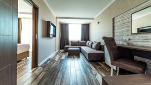 Uma sala de estar moderna com um sofá seccional, uma televisão de tela plana e piso de madeira.