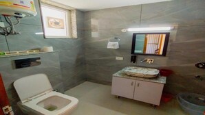 Um banheiro com vaso sanitário, pia com bancada de mármore, espelho e porta-toalhas.