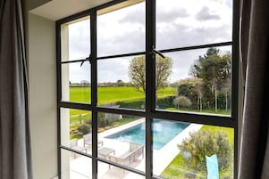 Janela com vista para uma piscina e paisagem verde.
