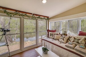 Quarto com uma grande janela com vista para um corpo de água, um telescópio em um tripé e uma cama aconchegante com roupa de cama estampada.