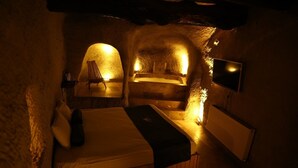 Um quarto acolhedor com uma cama, uma poltrona, uma televisão e uma lareira.