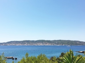 Paisagem costeira com vista clara para o mar, uma vila distante e um barco.