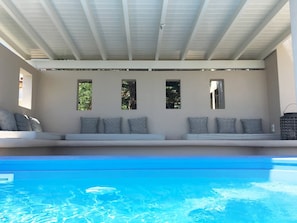 Área da piscina com espaço de estar e vista para a piscina.