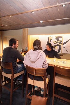 Teto de madeira, uma mesa com menu e parede com uma obra de arte em preto e branco.