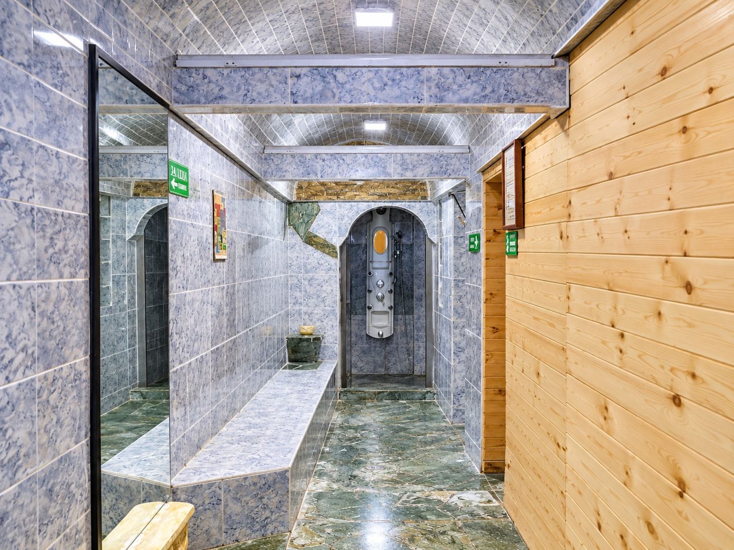 Uma sauna com parede de madeira, chão de mármore e um banco.